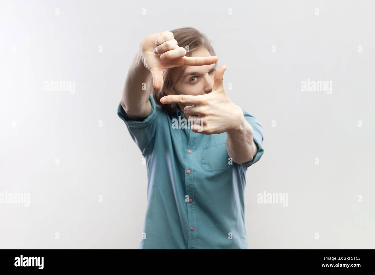 Portrait of man looking through frame of fingers gesturing photo ...