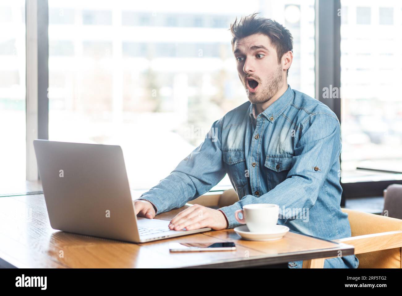Portrait of amazed astonished surprised man freelancer in blue jeans ...