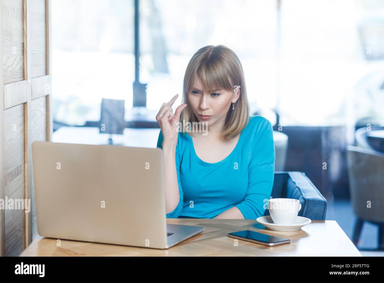Portrait of disappointed young woman with blonde hair in blue shirt ...