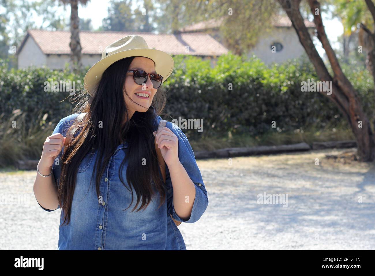 Latin adult woman in a hat and sunglasses looks happy, explores on a ...