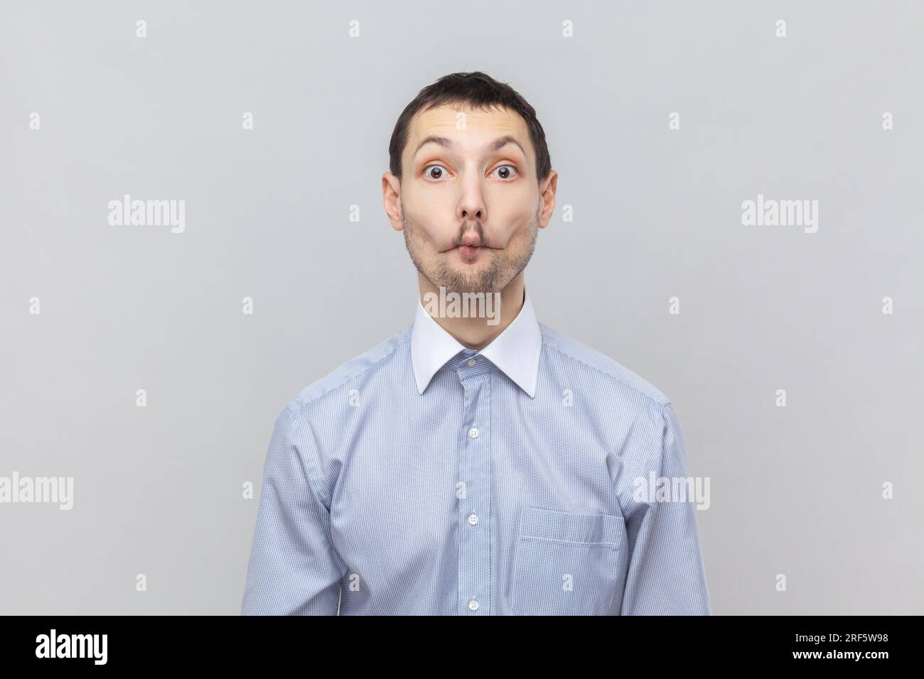 Portrait of funny childish young adult man standing looking at camera ...