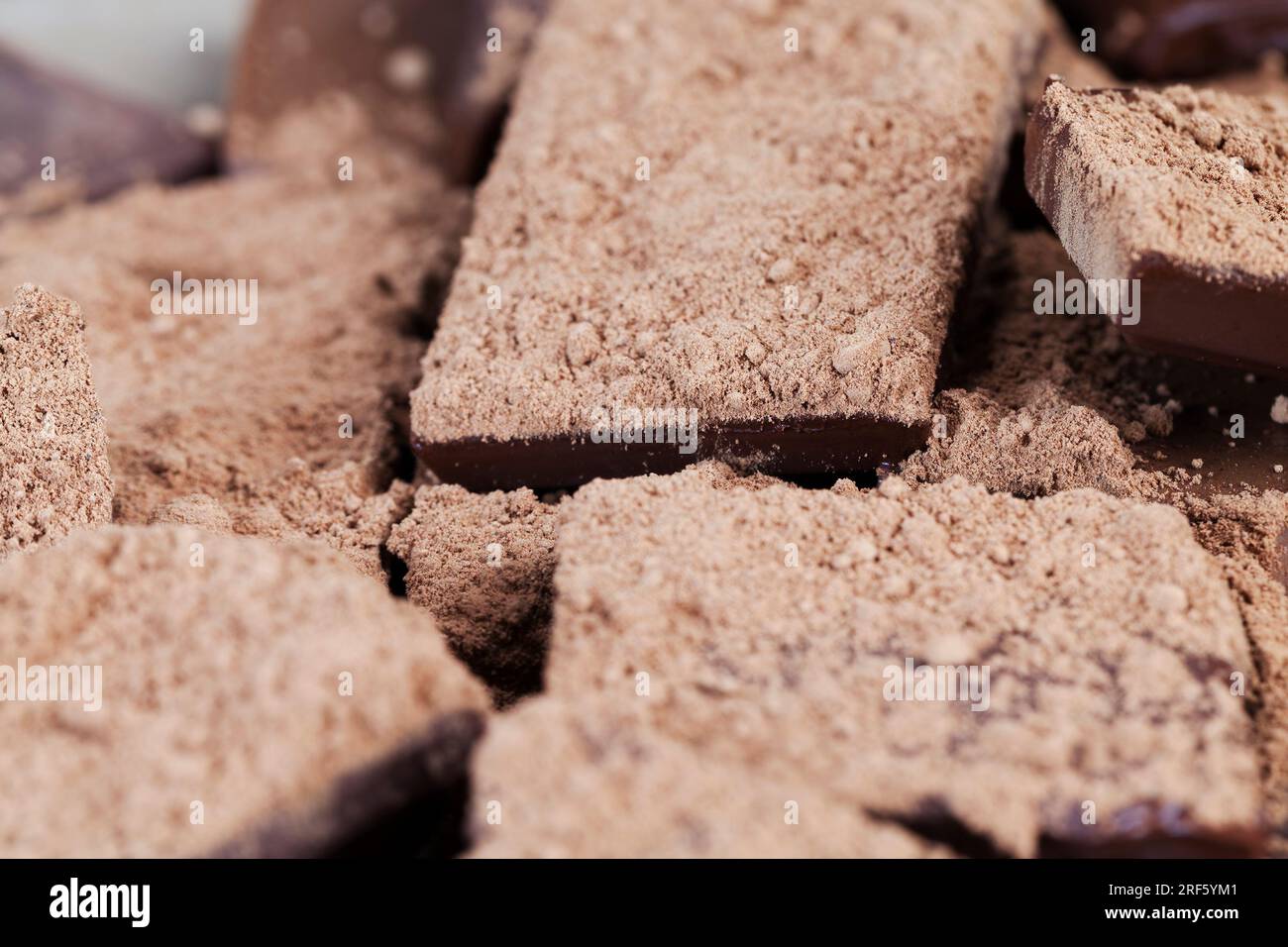 broken to pieces sweet chocolate bar with cocoa sprinkles, close up of ...