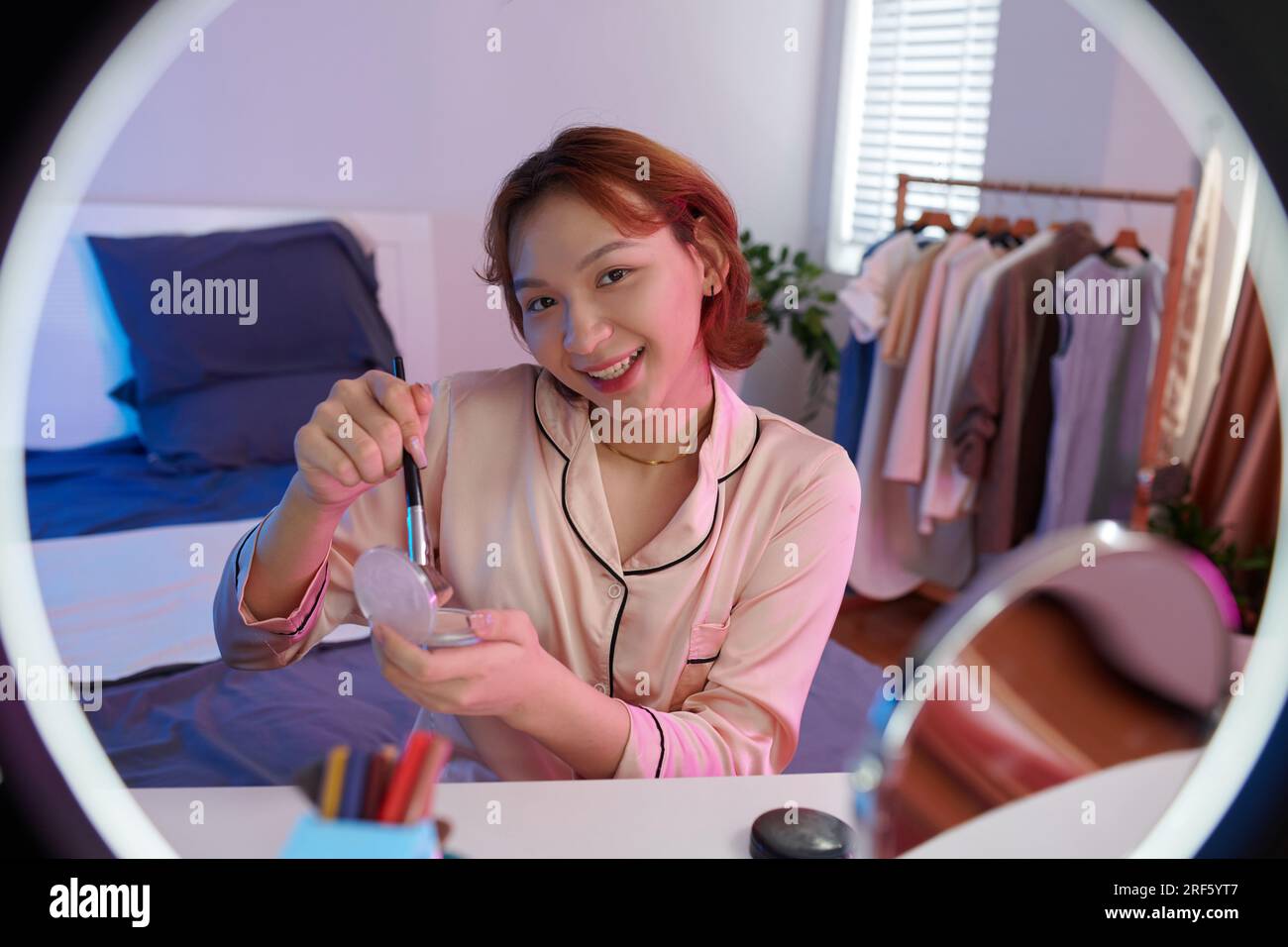 Happy young transgender woman filming herself applying makeup Stock ...