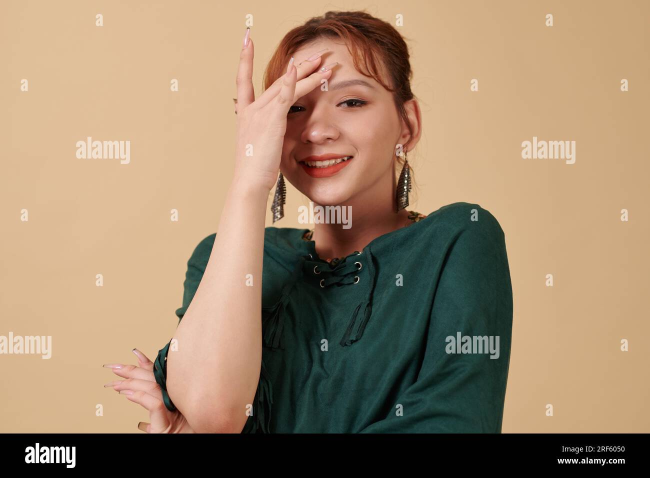 Portrait of cheerful young transgender woman with long nails touching ...