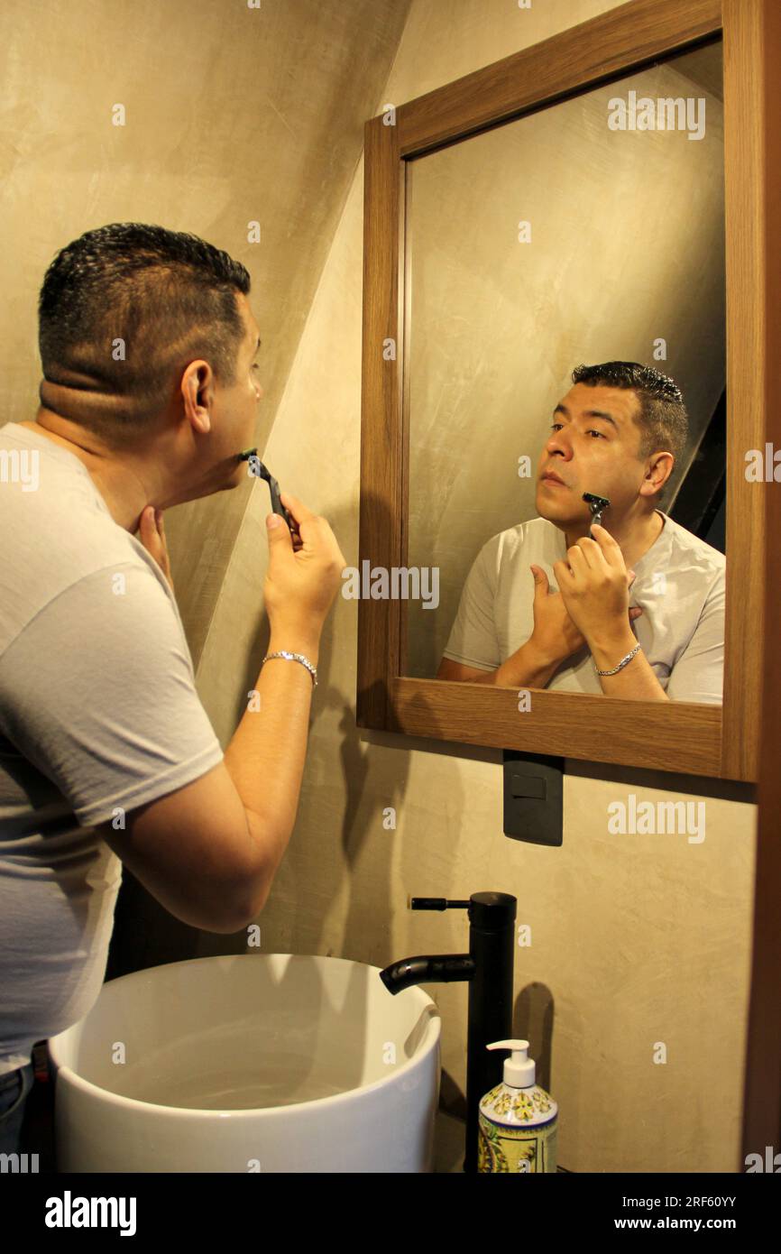 Dark-haired 40-year-old Latino man does his beauty routine, shaves with ...