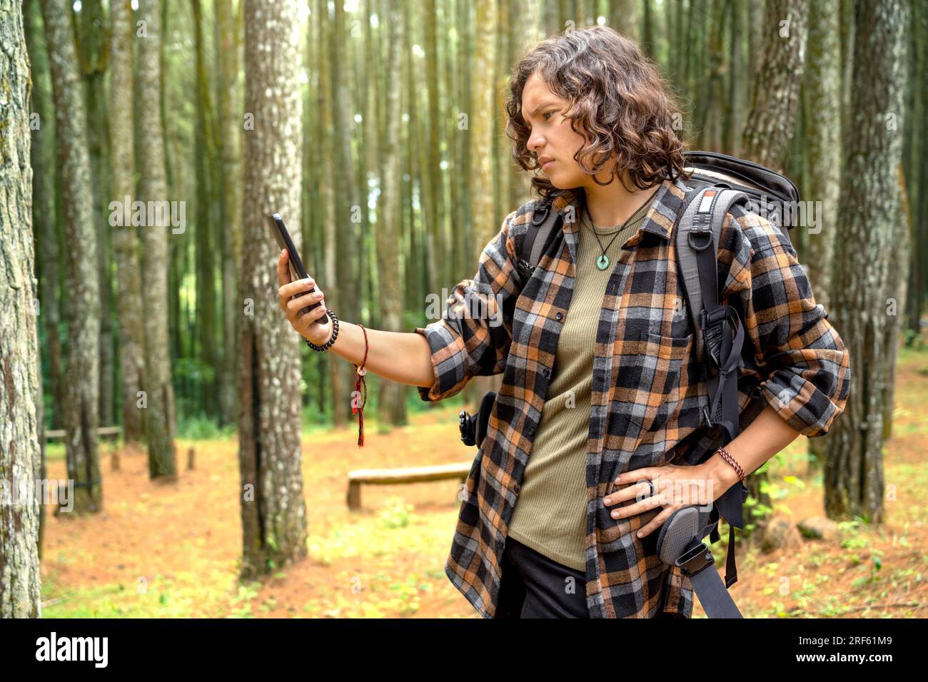 Asian woman trekking while using mobile phone in the forest. Traveling ...