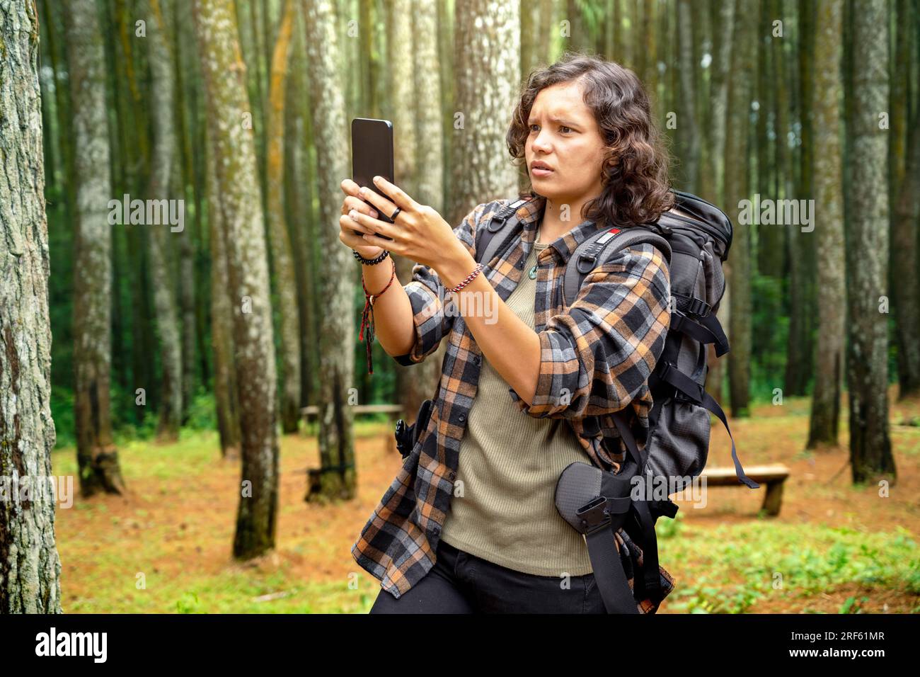 Asian woman trekking while using mobile phone in the forest. Traveling ...