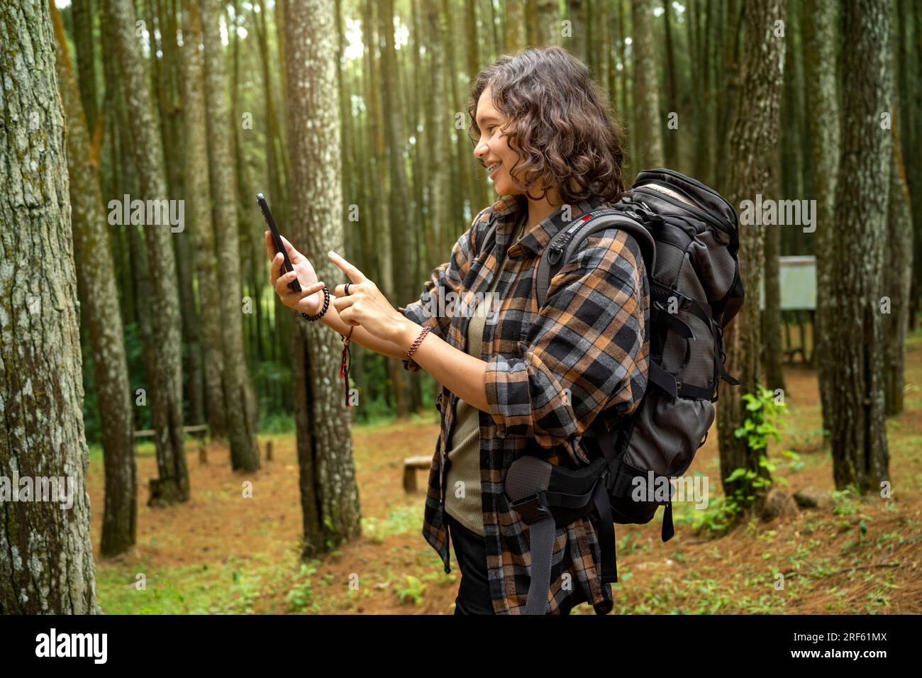 Asian woman trekking while using mobile phone in the forest. Traveling ...