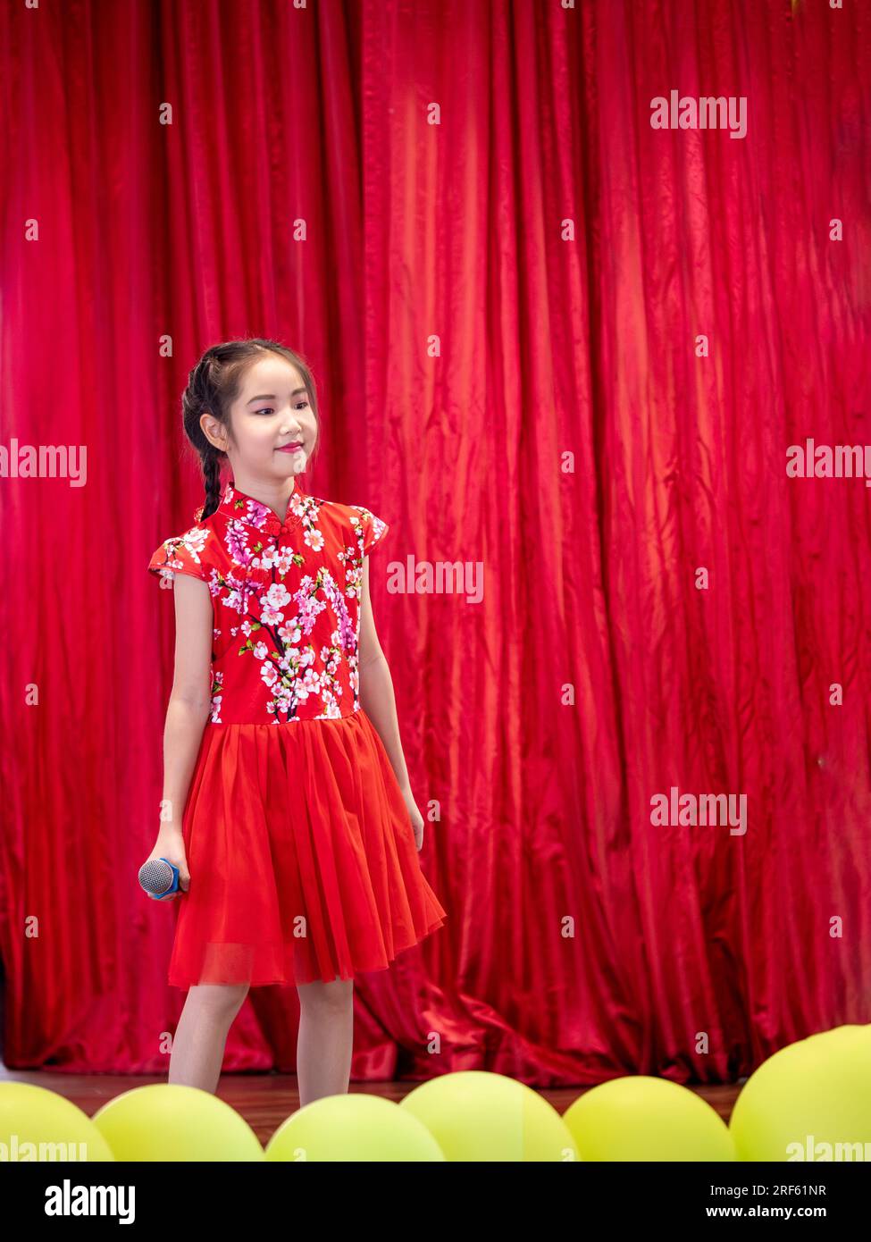 The Asian kid girl sing a song on stage at her school activity day ...