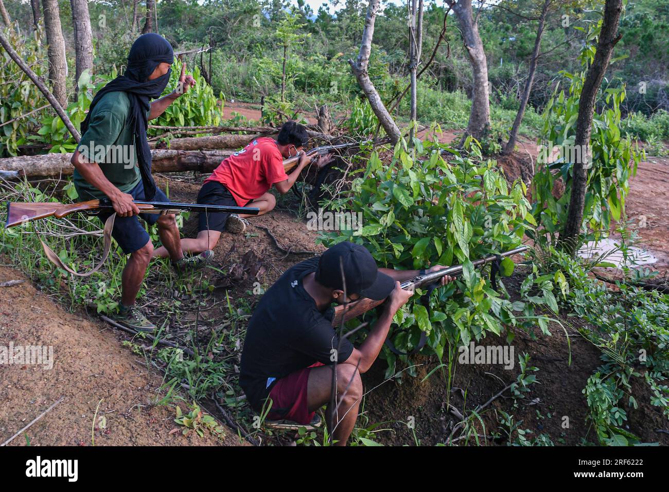 A squad leader trains a youth how to hide and shoot during enemy ...