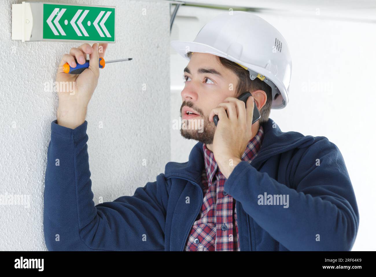young contractor working on exit sign Stock Photo - Alamy