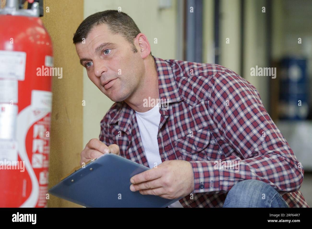 male professional checking a fire extinguisher using clipboard Stock ...