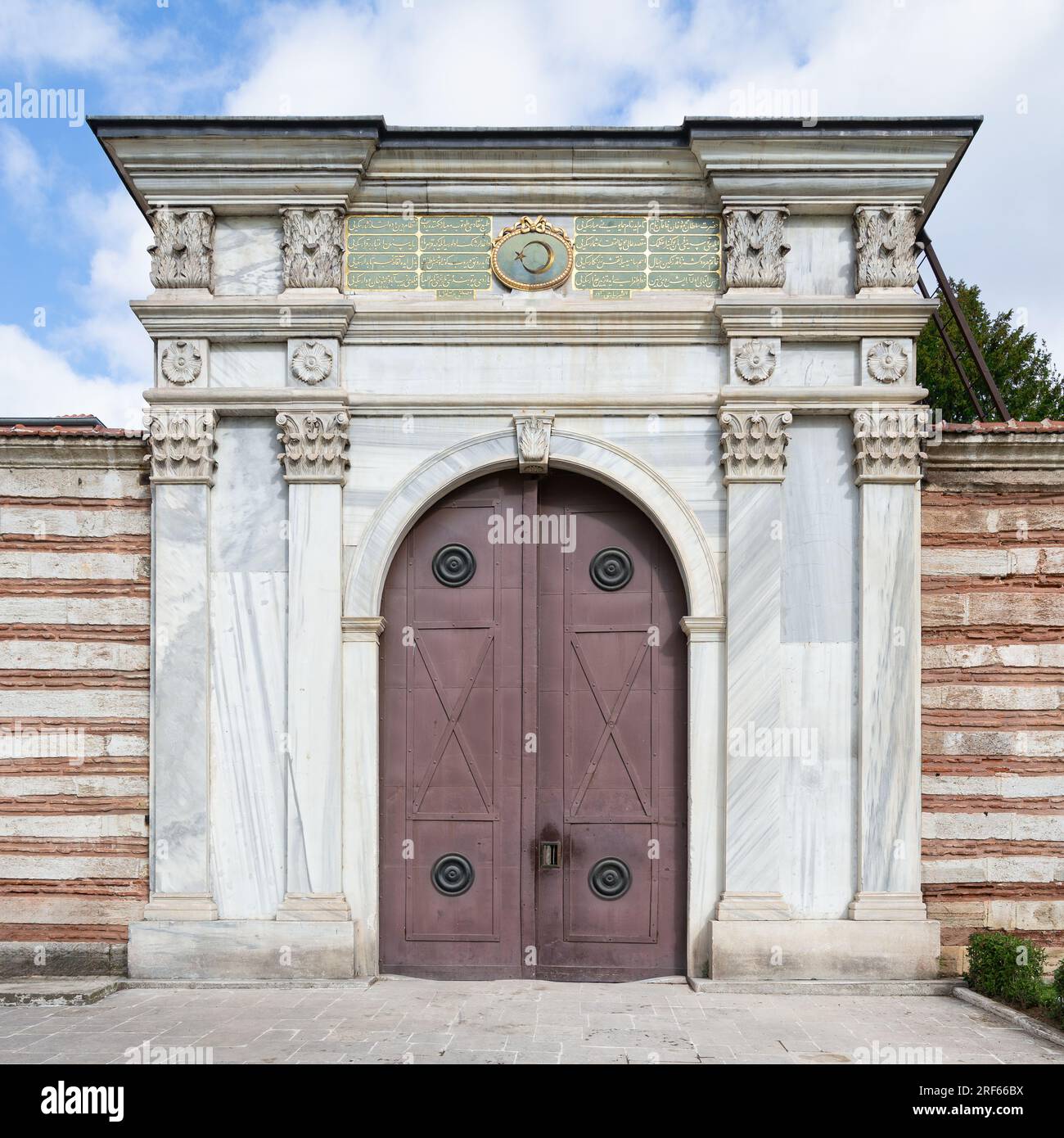 Decorated metal door with decorated white marble frame in stone brick ...