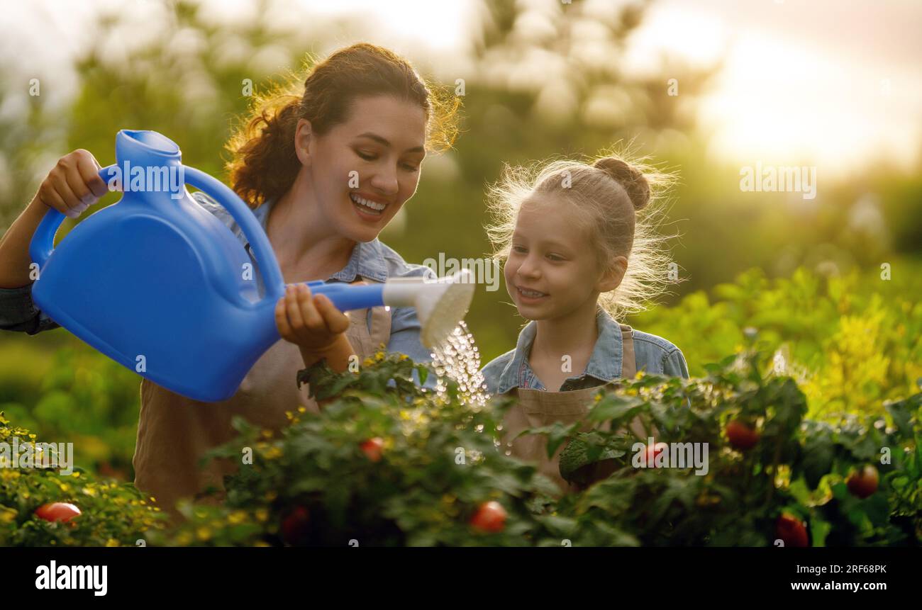 Happy mother and daughter gardening in the backyard. Kid helping her mom and learning botany ...
