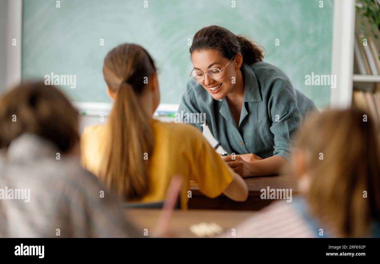 Happy kids and teacher at school. Woman and children are talking in the ...