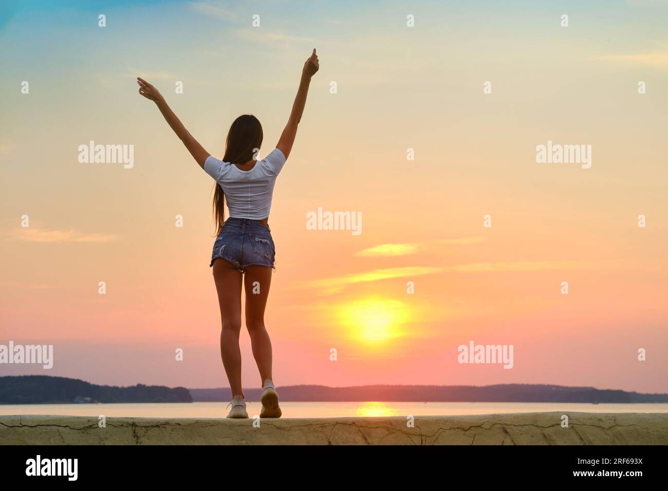 Cute woman meets sunset on a pier, back view Stock Photo - Alamy
