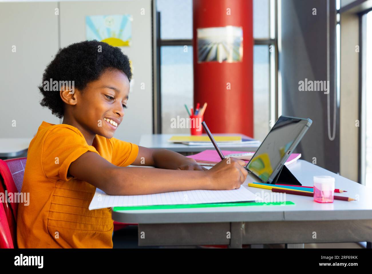 Happy biracial schoolboy having lesson on tablet video call in ...