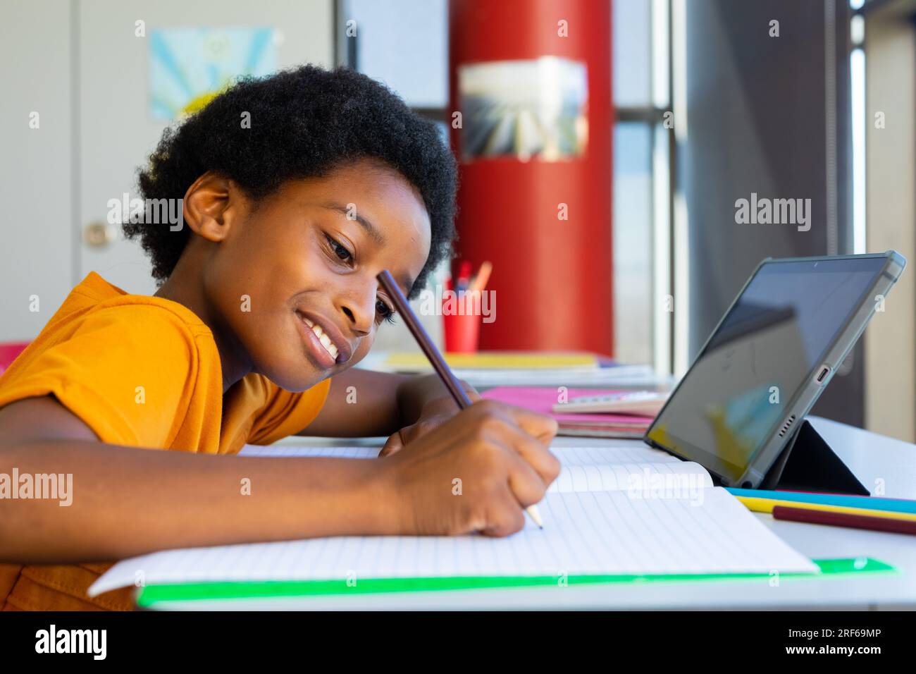 Happy biracial schoolboy having lesson on tablet video call in ...