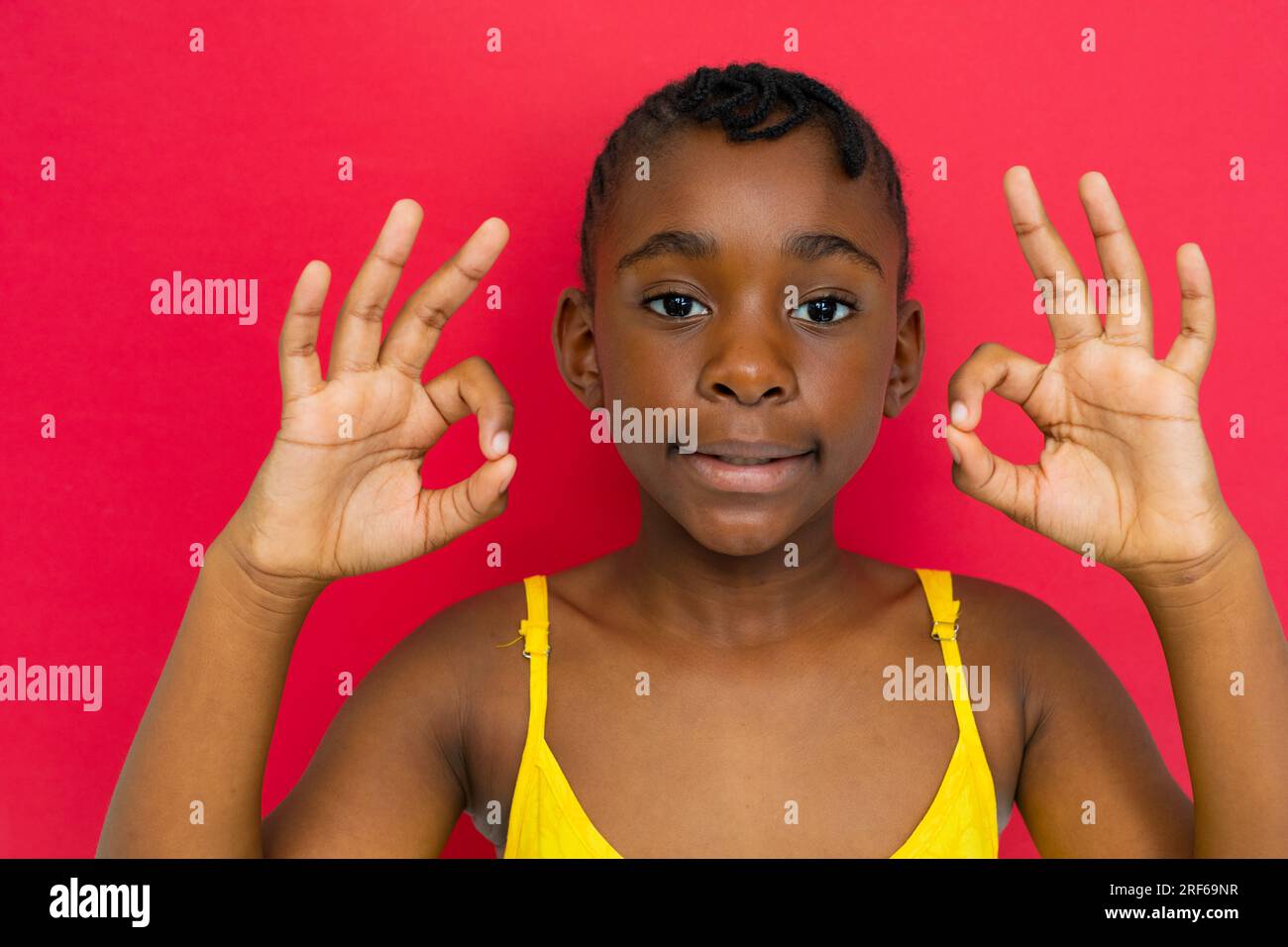 African american schoolgirl doing sign language with hand over pink ...