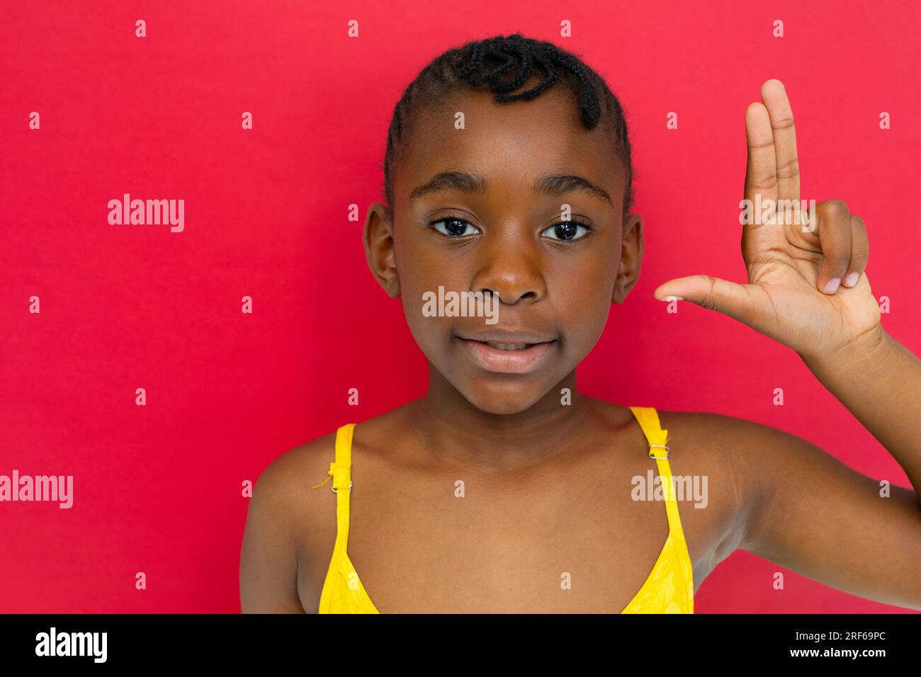 African american schoolgirl doing sign language with hand over pink ...