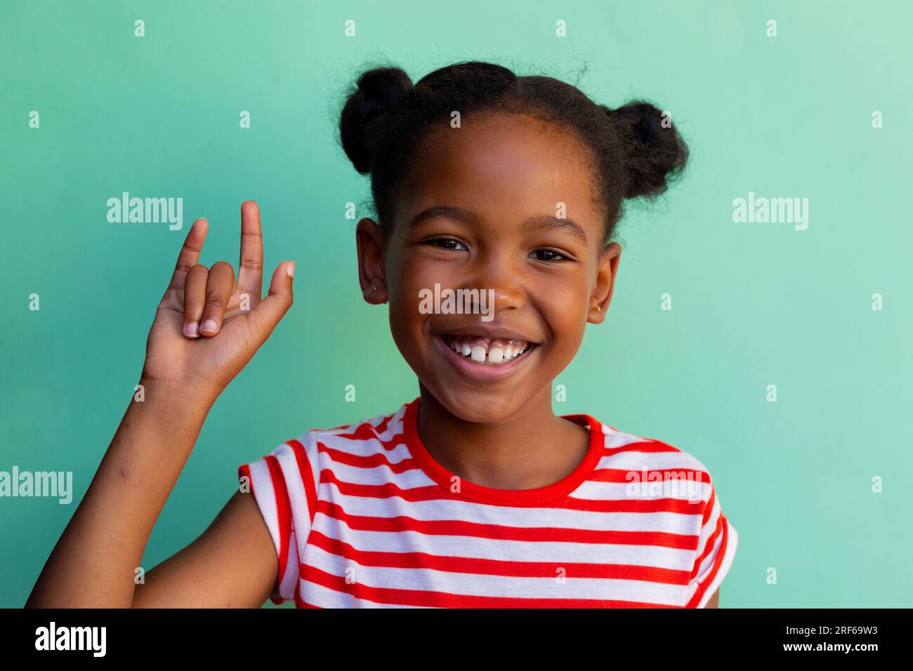 African american schoolgirl doing sign language with hand over blue ...