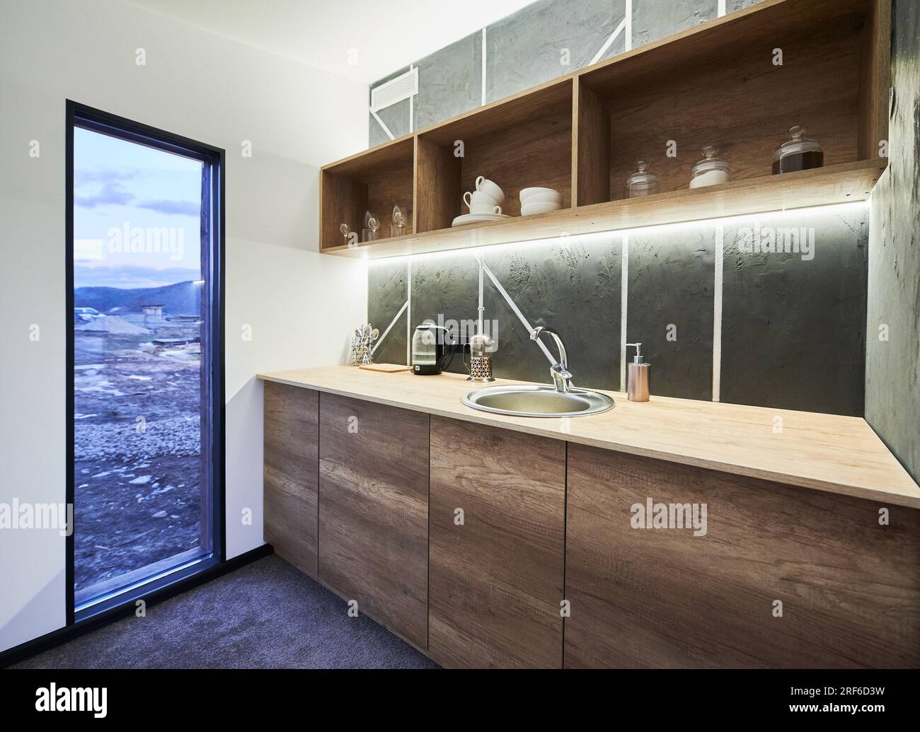 Modern kitchen with white walls and glass door with scenic view inside ...