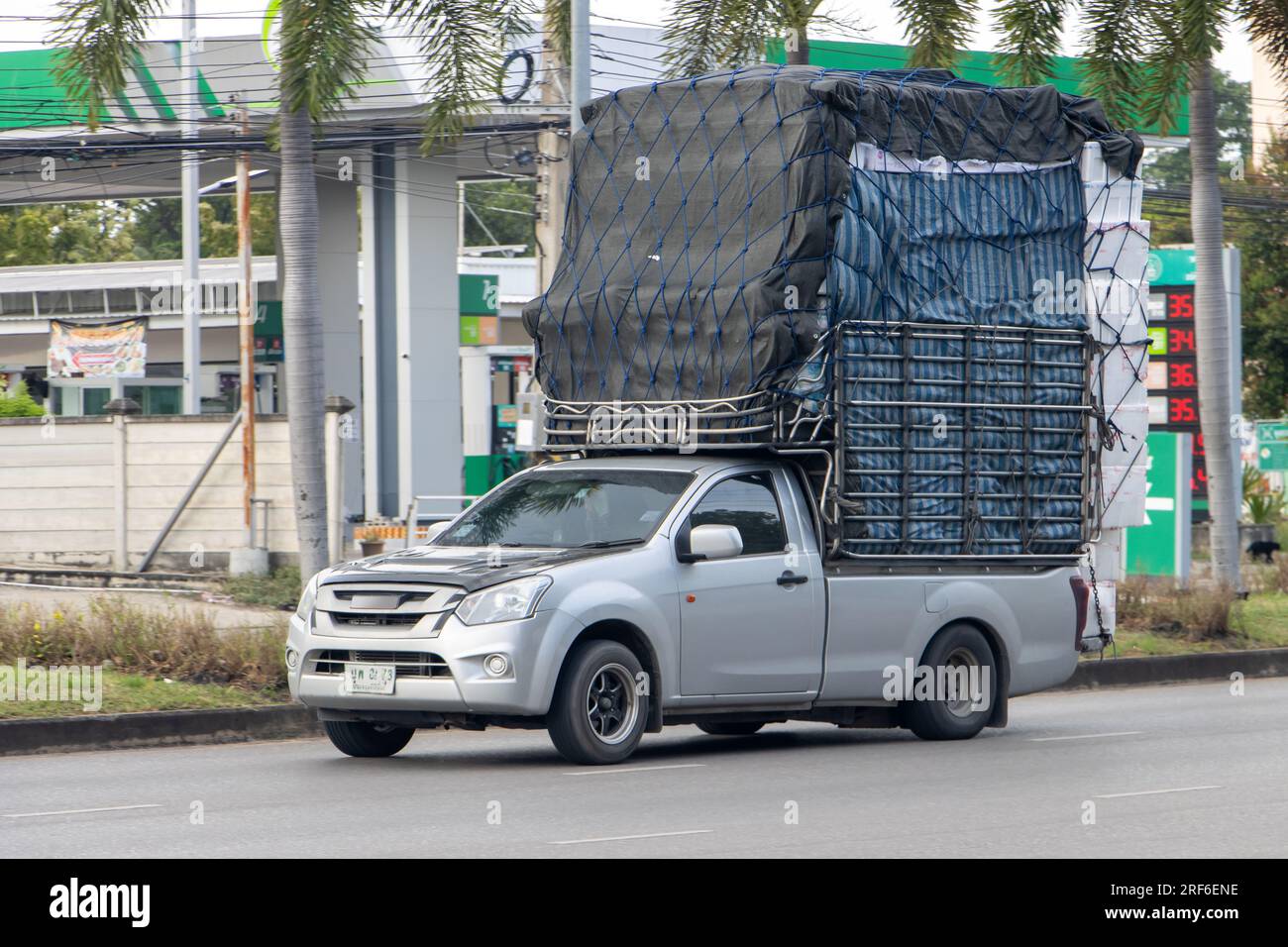 A pickup truck loaded with boxes drives down a city street, Thailand ...