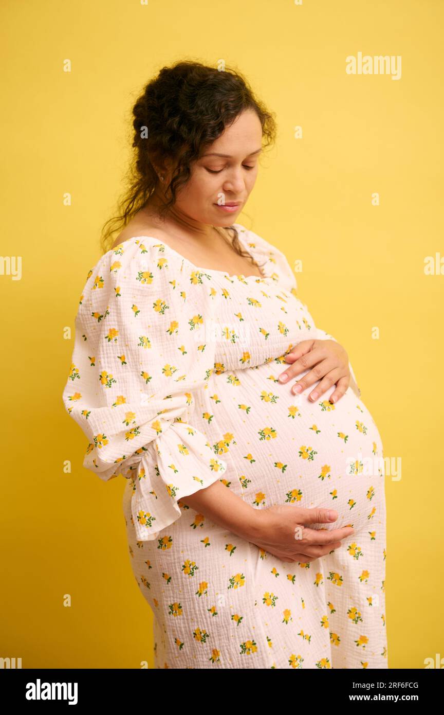 Pregnant woman, gravid female expecting a baby, gently stroking her big ...