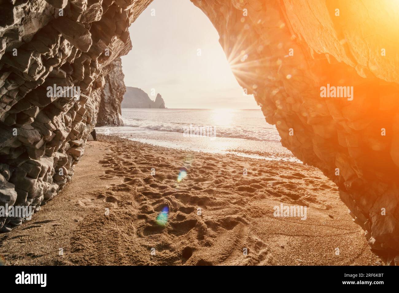 sunset seascape, captured from a rocky volcanic cave, view of the beach ...