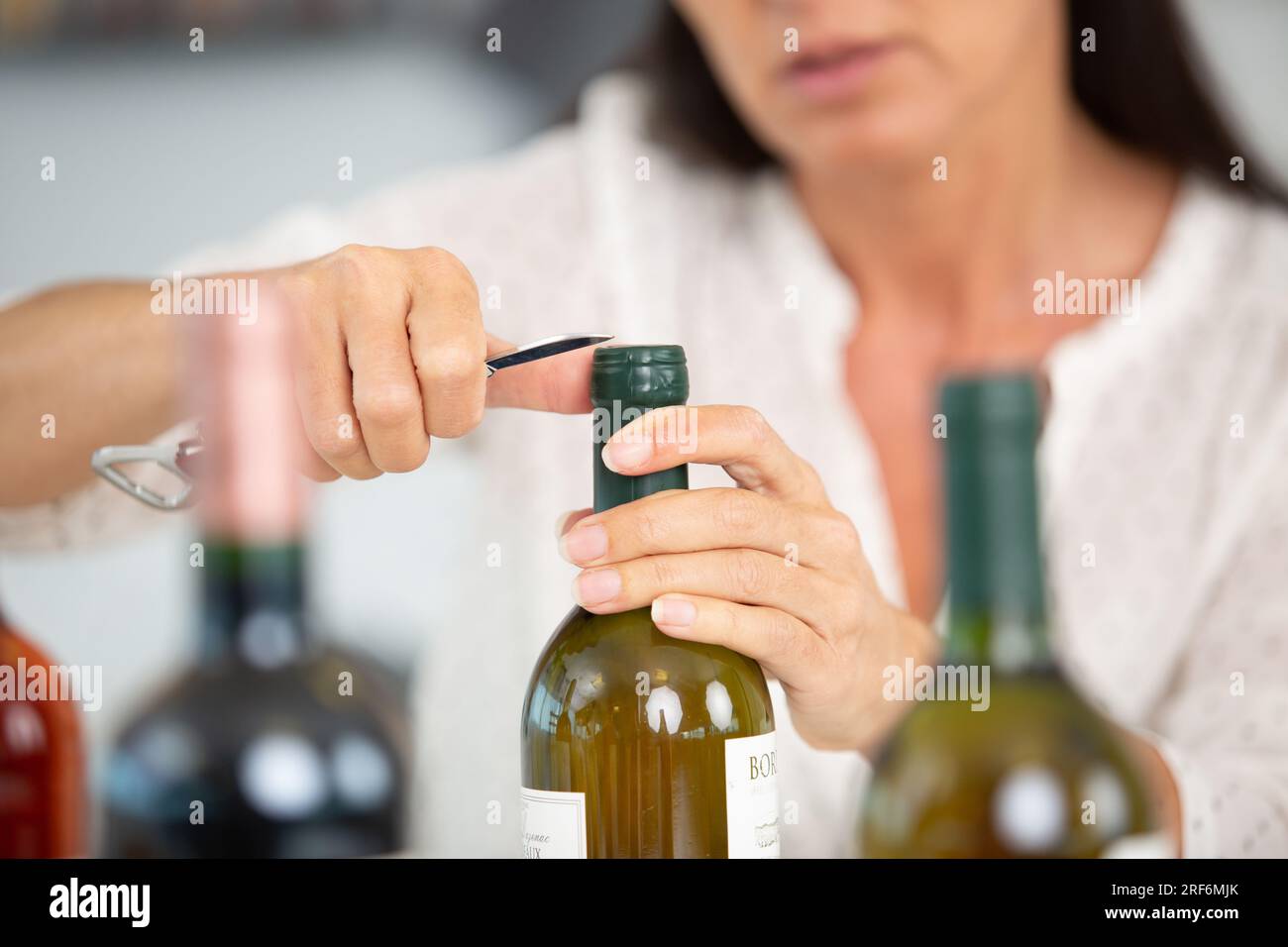 happy mature woman uncorking a wine bottle Stock Photo - Alamy