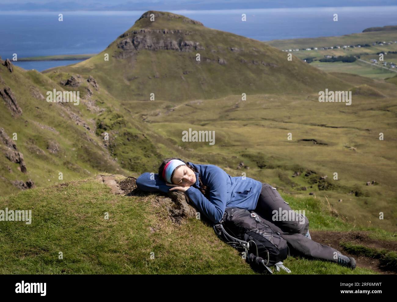 Young woman is lying on the meadow on mountain range Quiraing. It is a ...