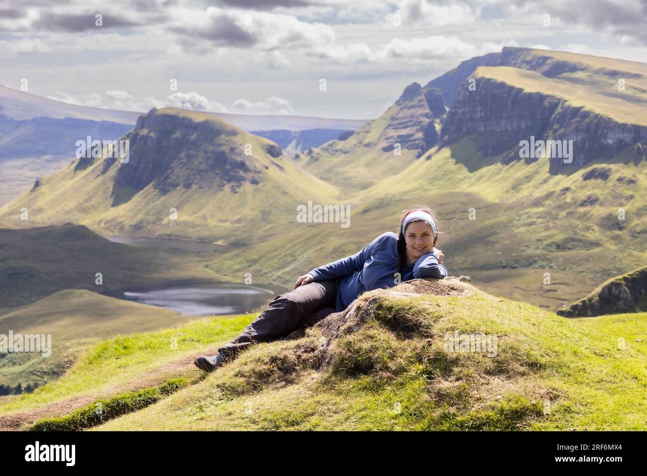 Young woman is lying on the meadow on mountain range Quiraing. It is a ...