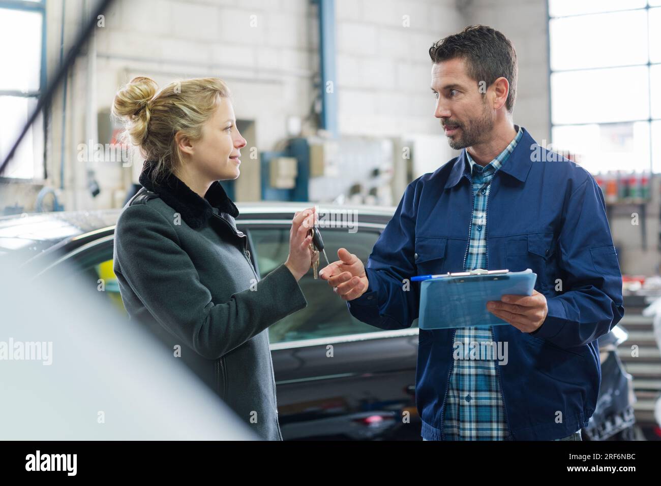 female garage customer giving car key to mechanic Stock Photo - Alamy