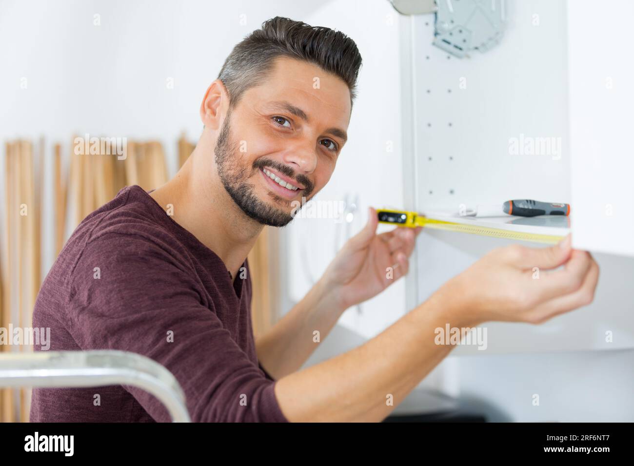 man smiling while measuring the cupboard Stock Photo - Alamy