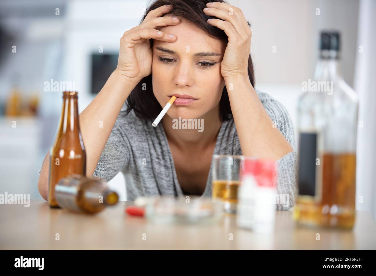 depressed woman is smoking and drinking at kitchen table Stock Photo ...