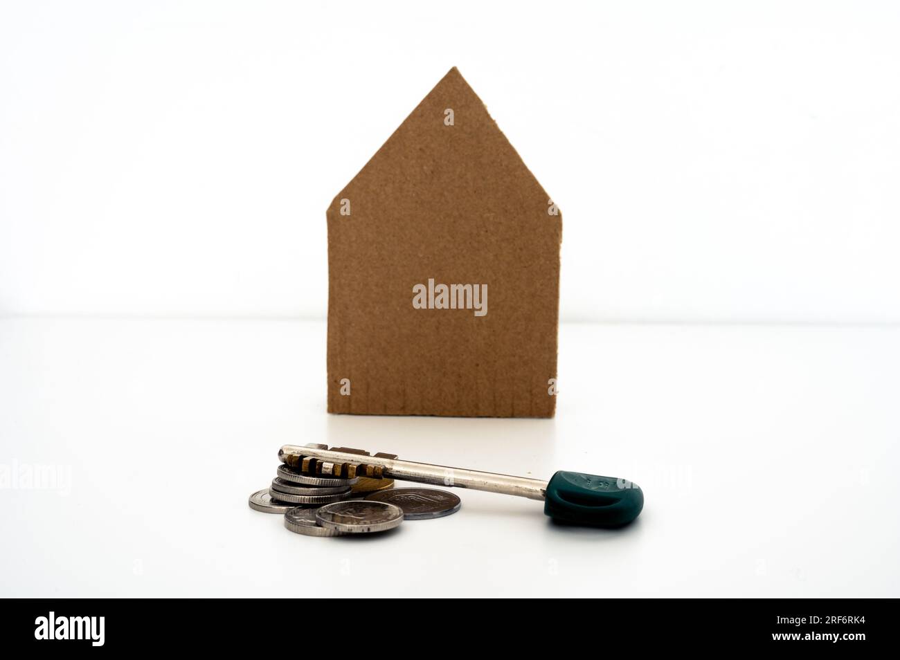 One key on coins in front of paper house. Mortage, housing, finance ...