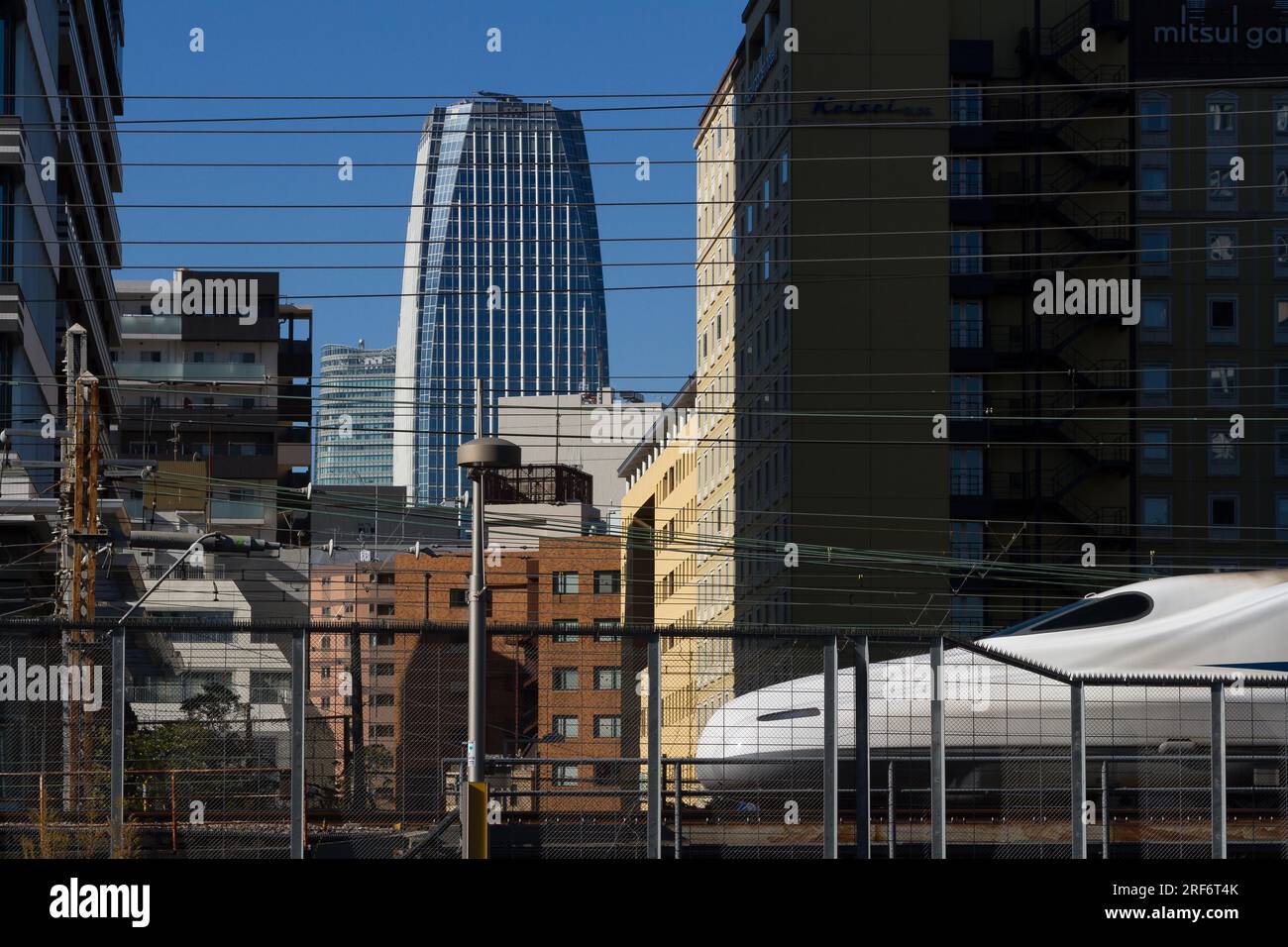 An N700 series shinkansen bullet train passes through buildings in ...