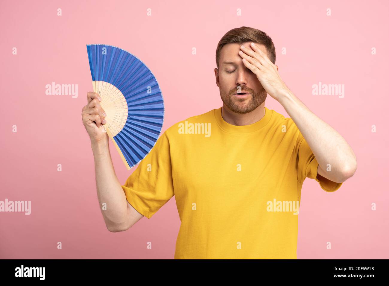 Sweaty tired man touching forehead using paper fan suffer from heat ...