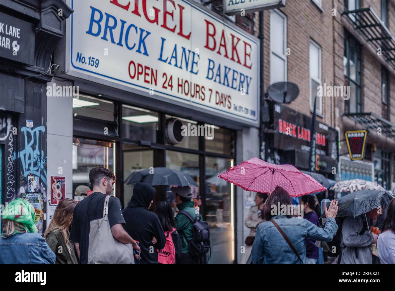 Tourists and Londoners queue up in the rain outside the Brick Lane ...