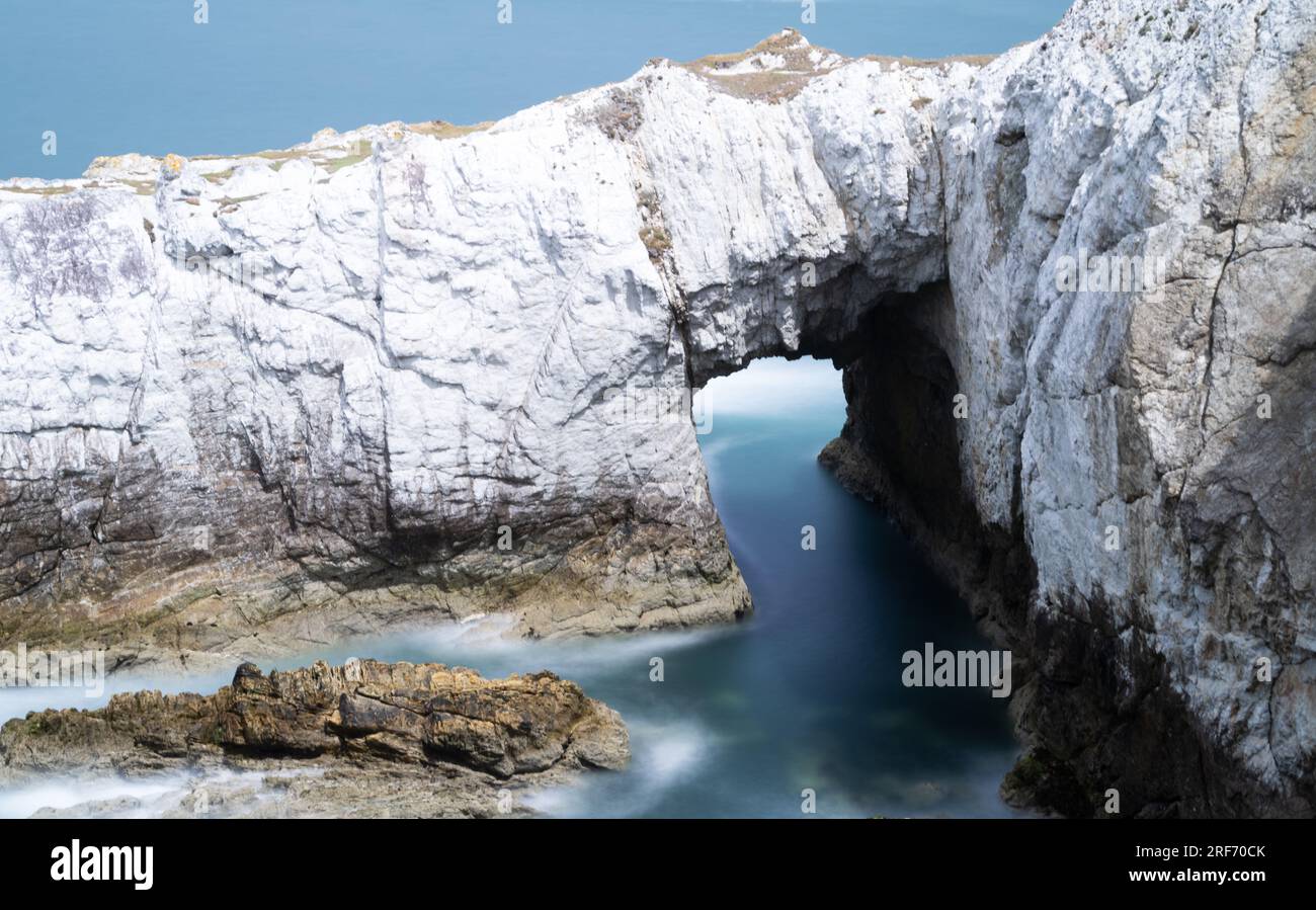 Long exposure of the sea under a white cliff and sea arch. Silky smooth ...