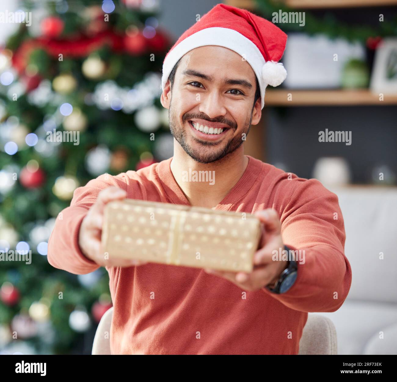 Christmas, portrait and asian man with gift giving in his home for ...