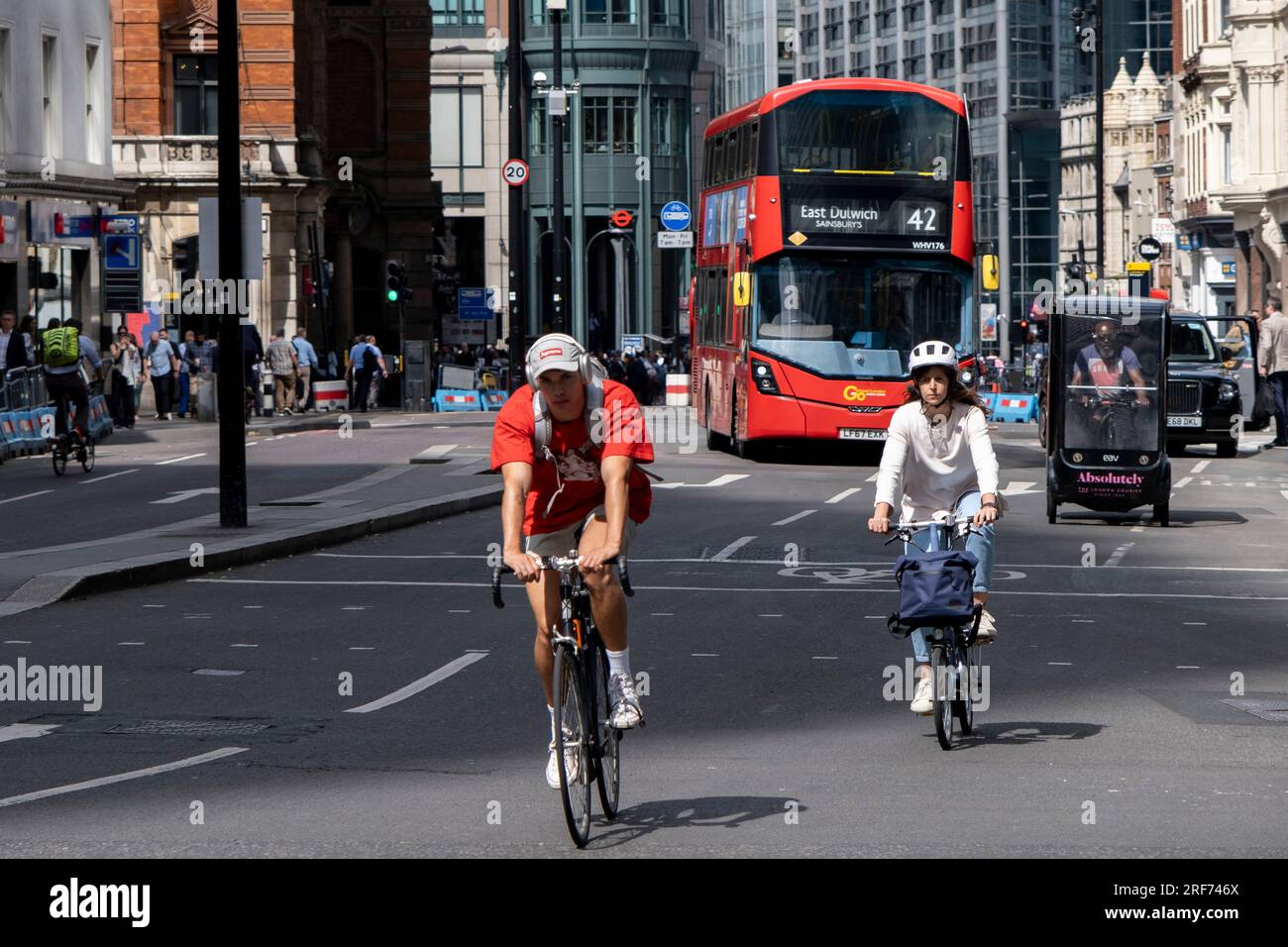 Cyclists in the City of London interacting with public transport buses on 6th July 2023 in ...