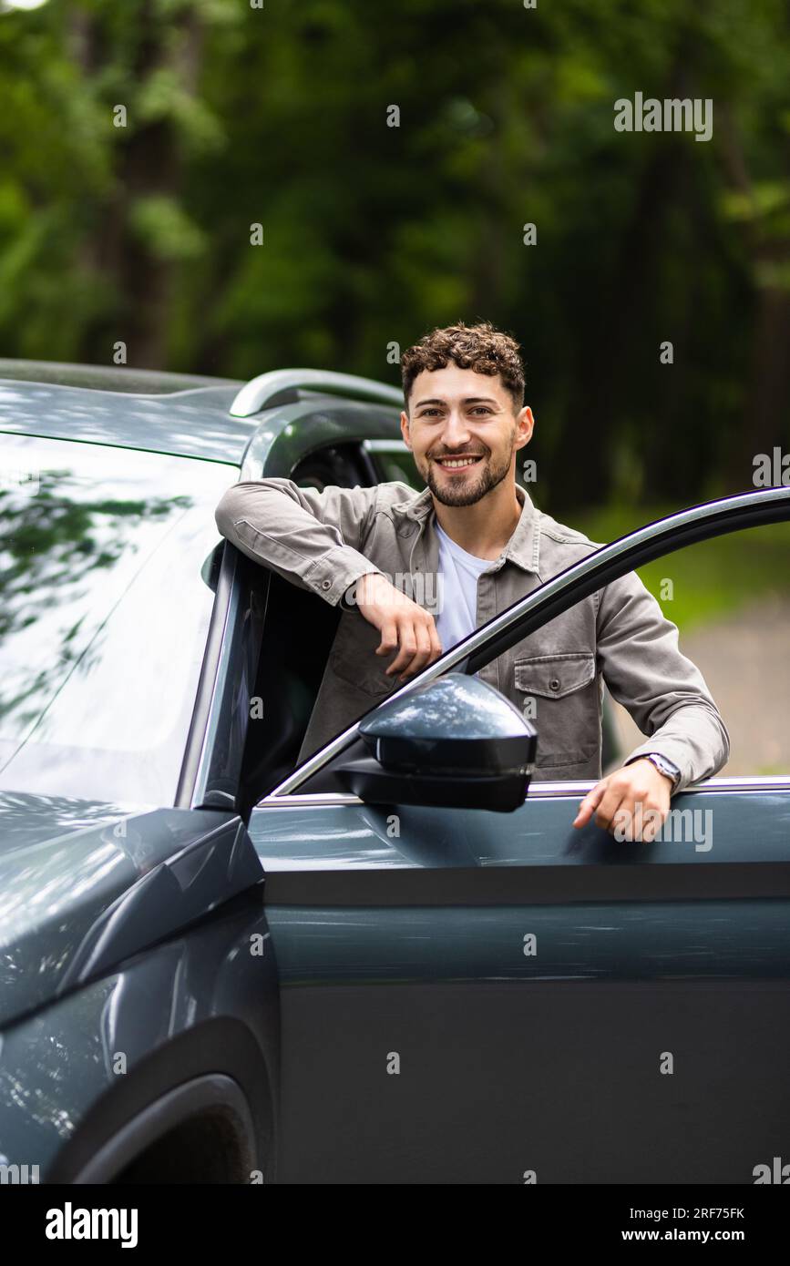 Smiling man standing next to his car Stock Photo - Alamy