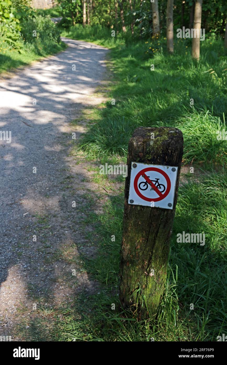 Sign prohibiting bikes on wooden post alongside path Stock Photo - Alamy