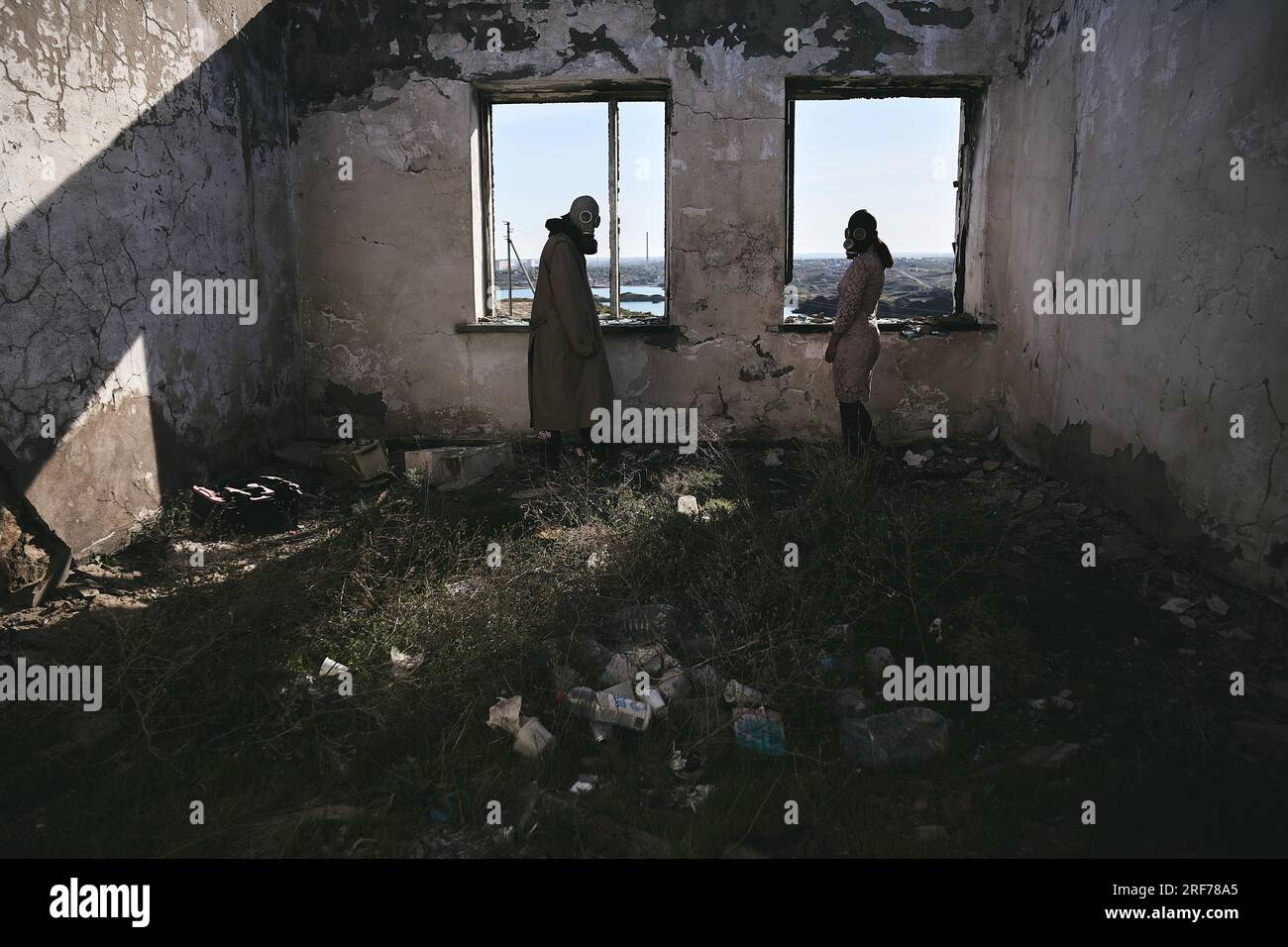 Two people, a guy and a girl in gas masks, stand inside an abandoned ...
