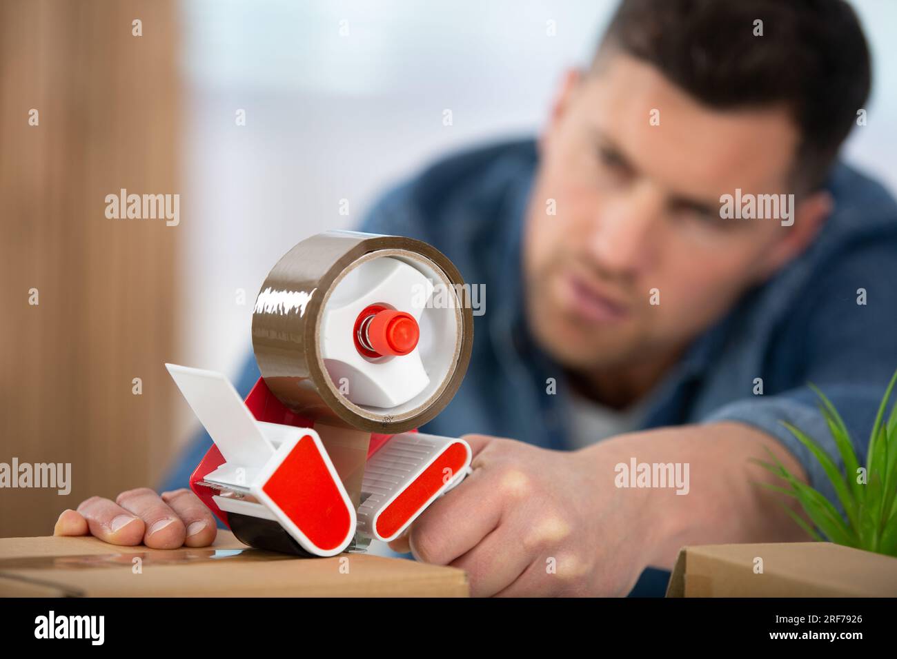 man closing a cardboard box with tape at home Stock Photo - Alamy