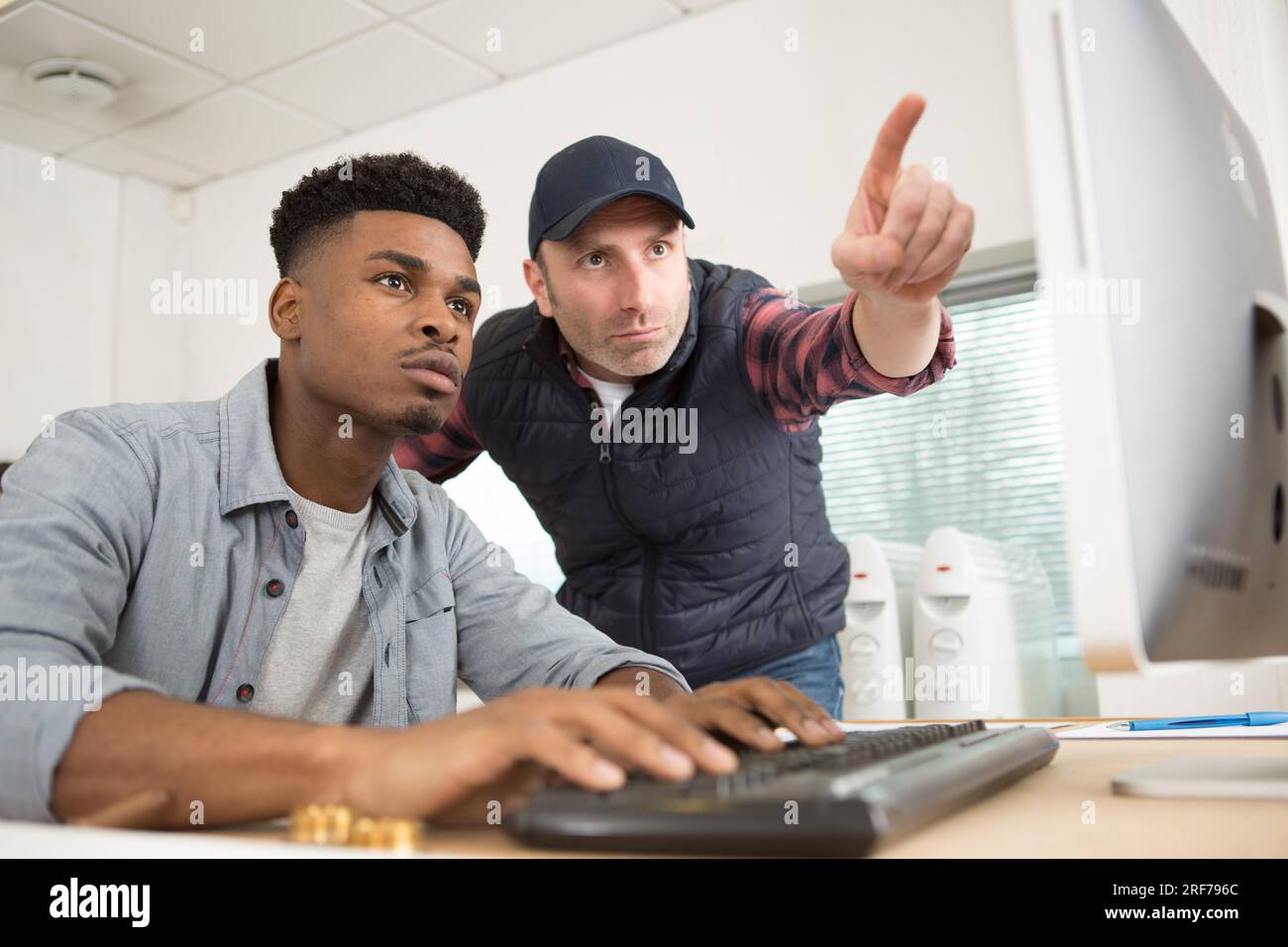 supervisor behind student using computer pointing to the monitor Stock ...
