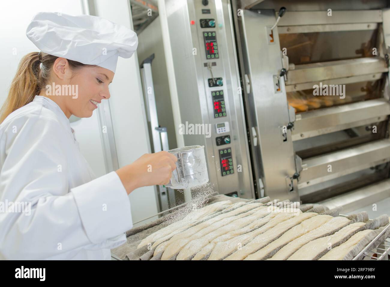 Chef shaking flour over baguettes Stock Photo - Alamy
