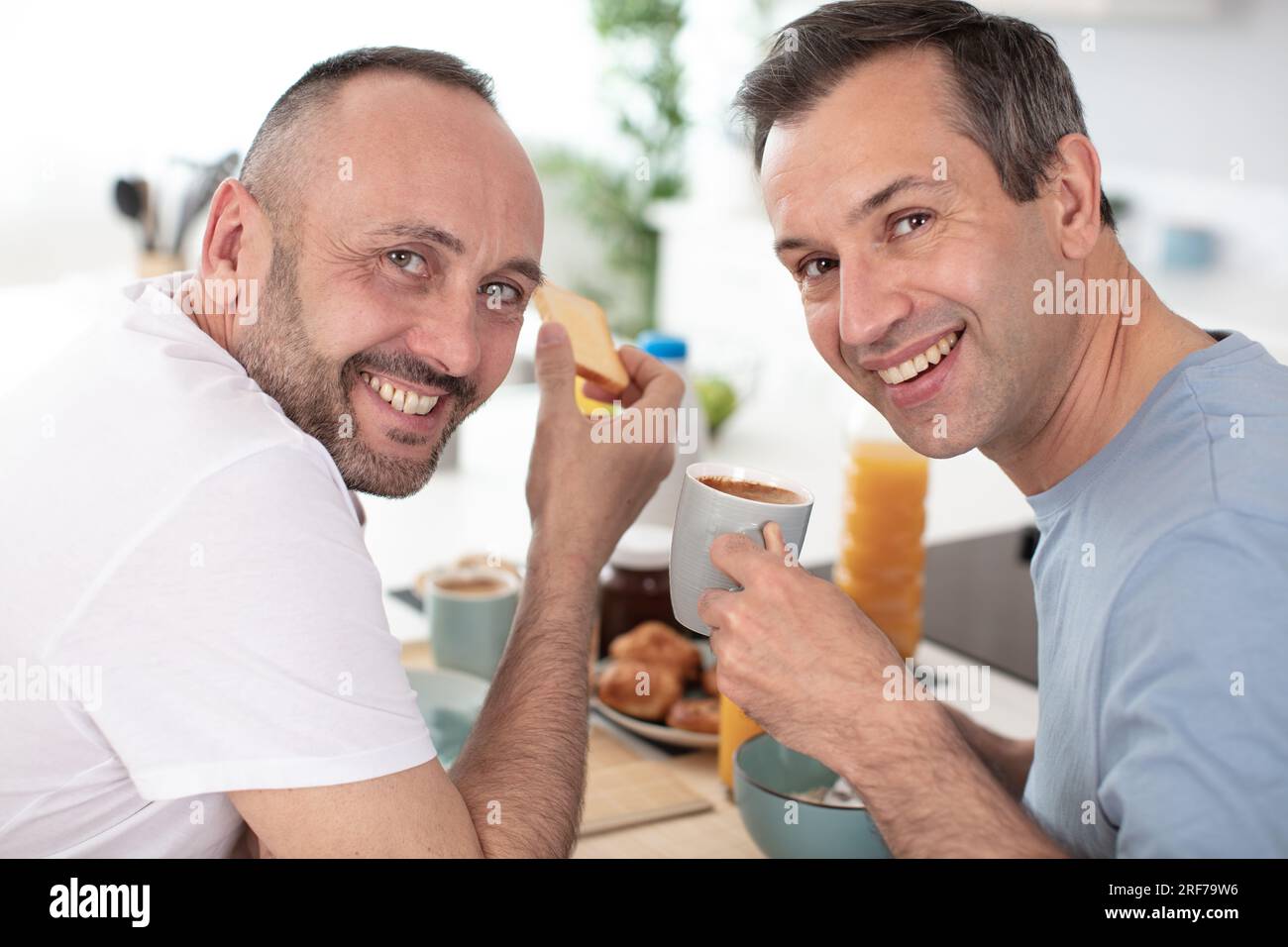smiling gay couple talking and eating breakfast together Stock Photo ...