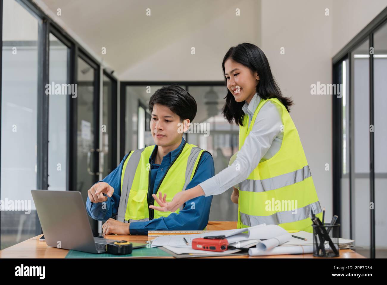 Two young man and woman engineers meeting, working, discussing, planing ...